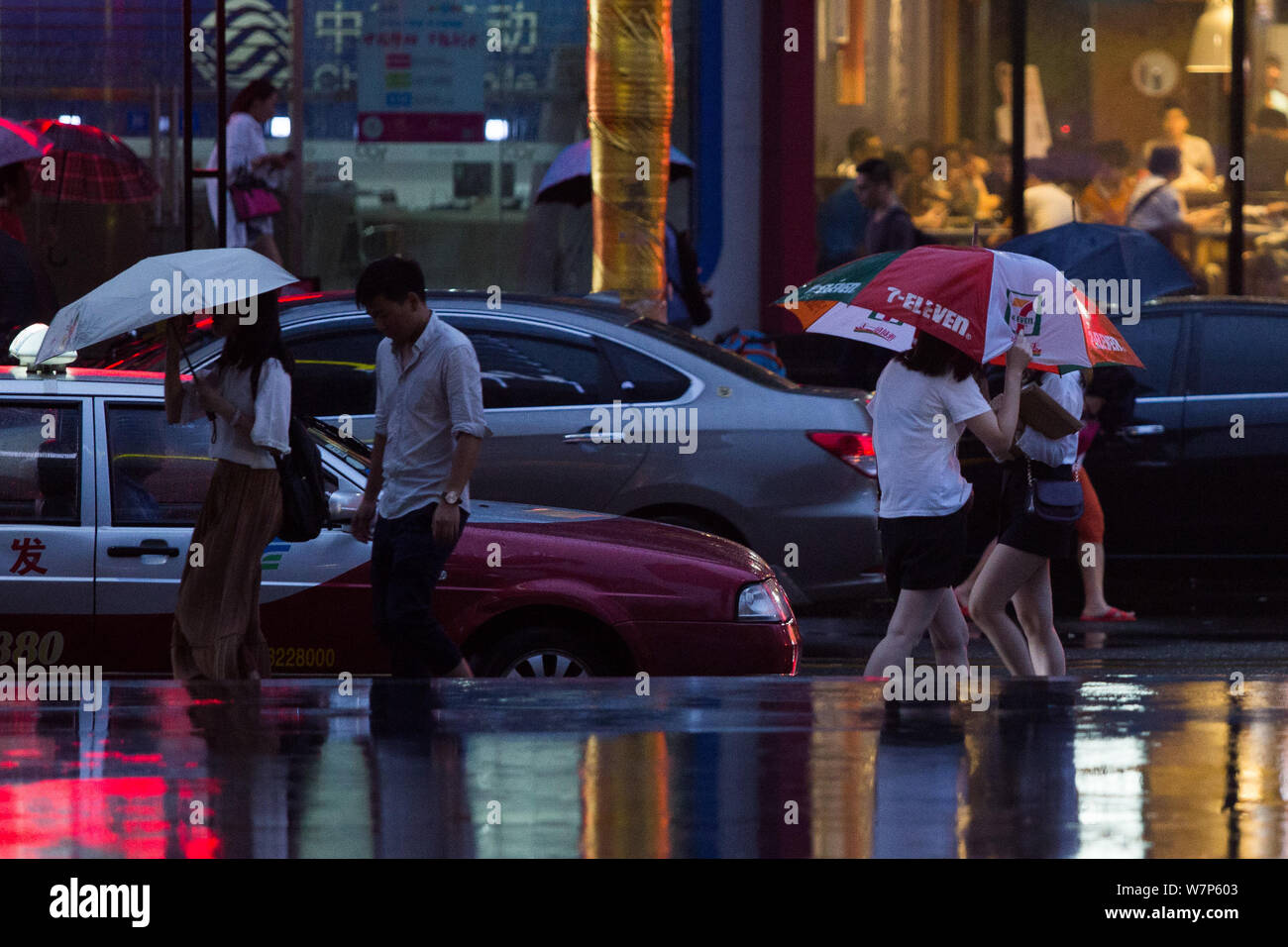 Chinese commuters struggle with their umbrellas in heavy rain and ...