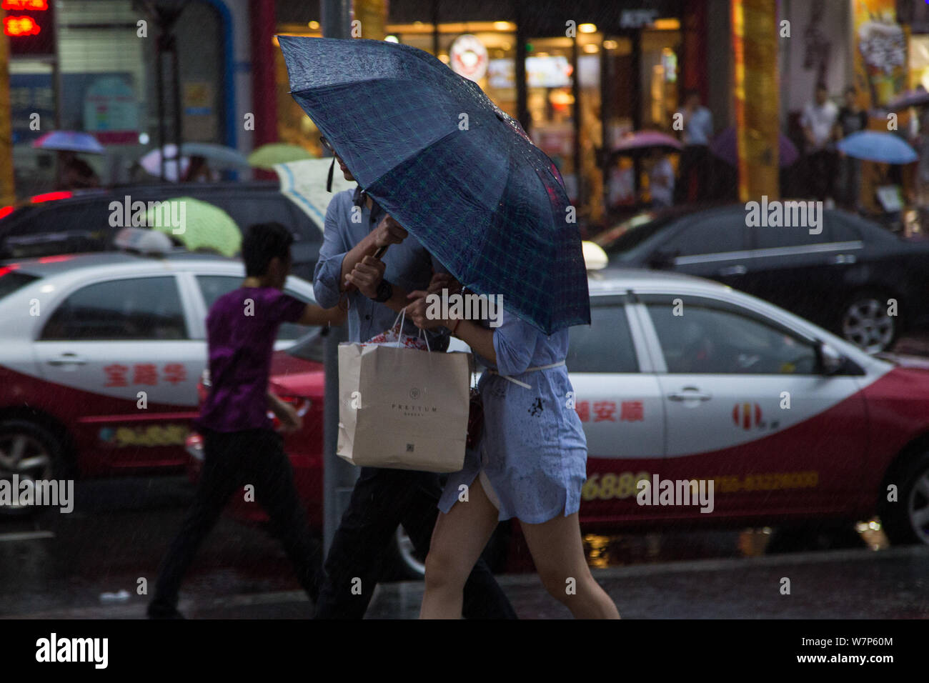 Chinese commuters struggle with their umbrella in heavy rain and strong ...