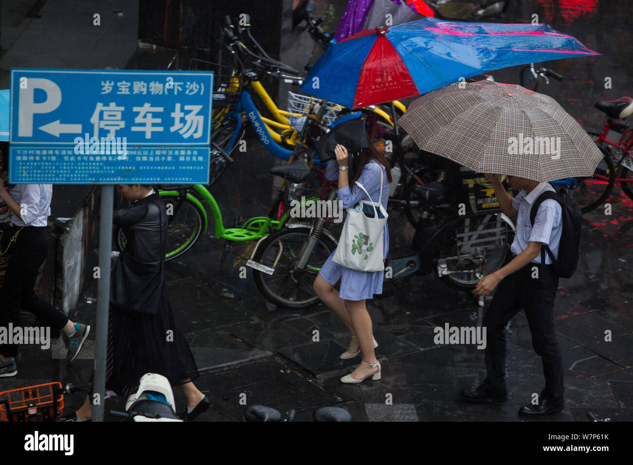 A Chinese commuter shields herself with her bag from heavy rain caused ...