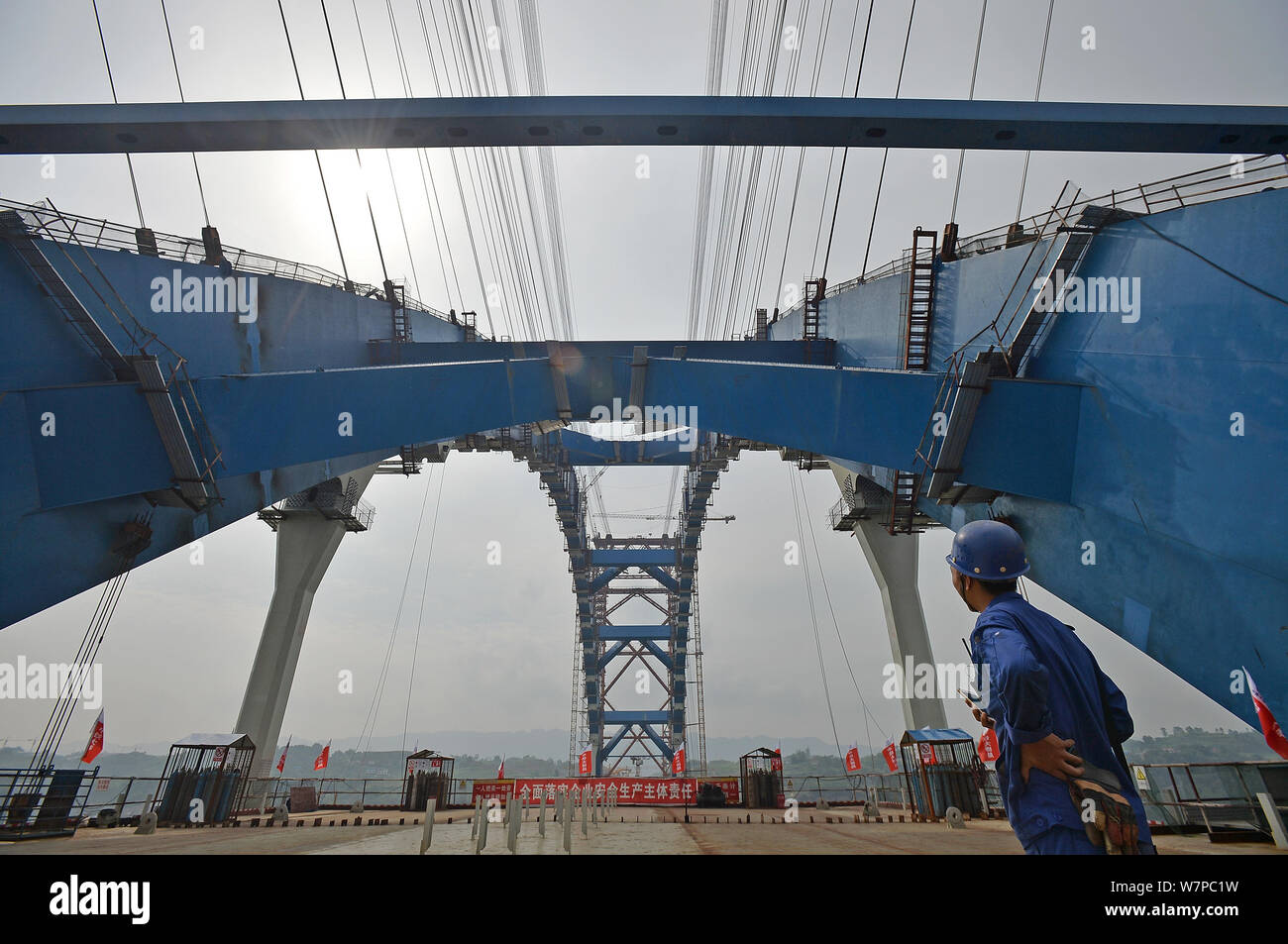 A Chinese worker looks at the Yibin Jinsha River Railway Bridge, the ...