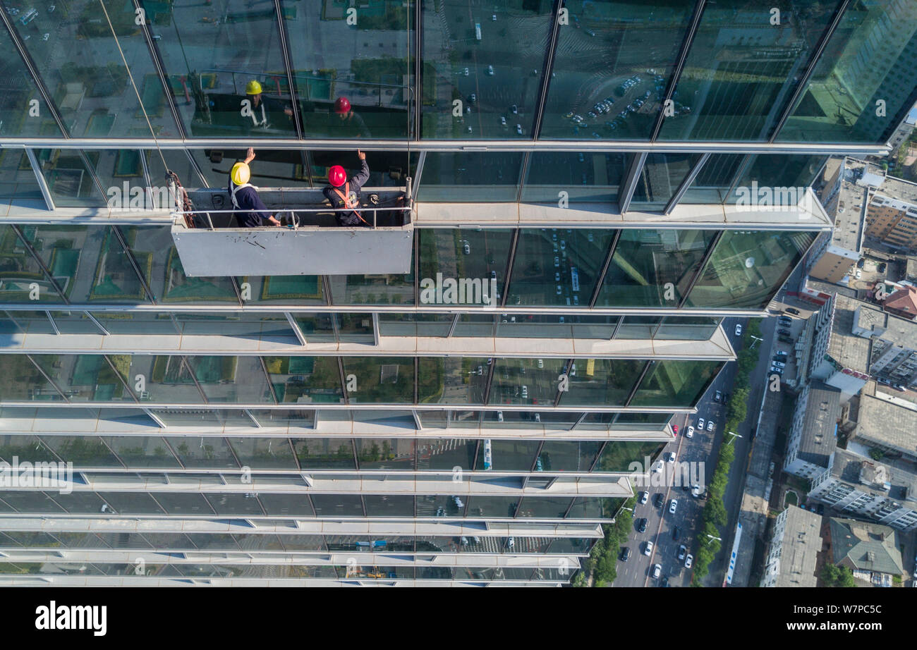 Chinese migrant workers clean the exterior window of the 350-meter-high ...