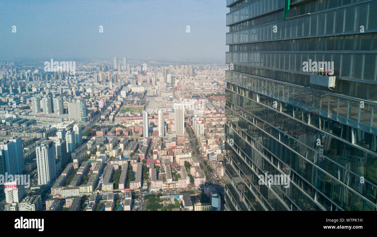 Chinese migrant workers clean the exterior window of the 350-meter-high ...