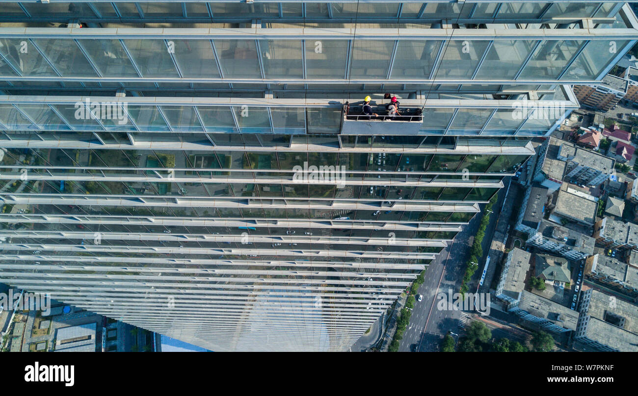 Chinese migrant workers clean the exterior window of the 350-meter-high ...