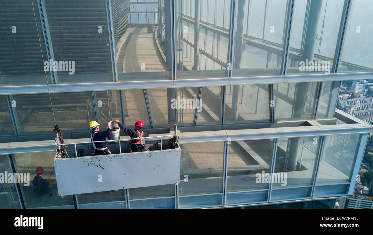 Chinese migrant workers clean the exterior window of the 350-meter-high ...
