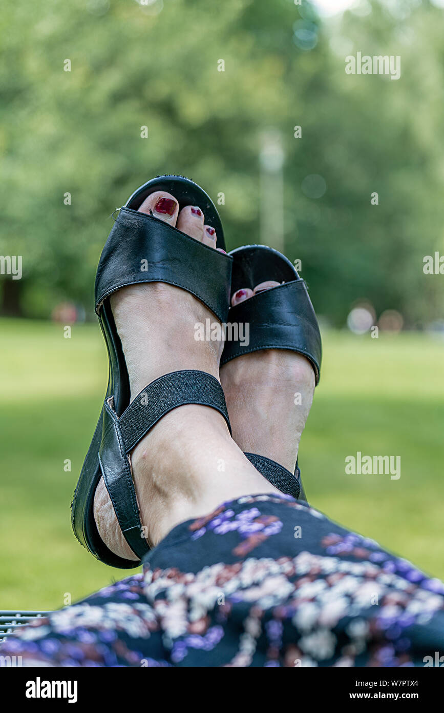 Putting up female feet with sandals with a park background for a break ...