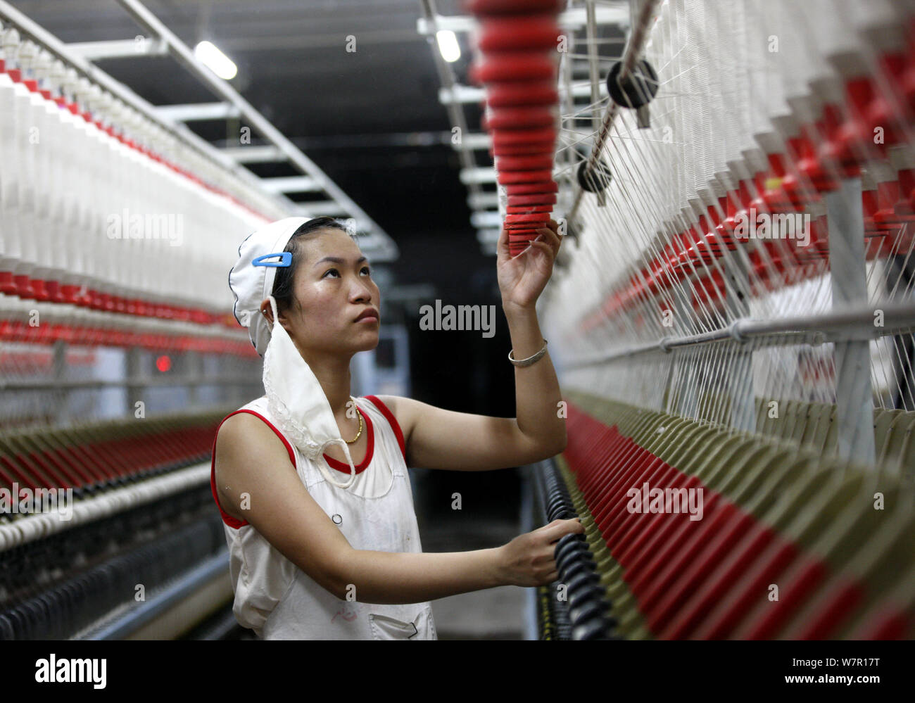A female Chinese worker handles production of yarn to be exported to Southeast Asia on a ...