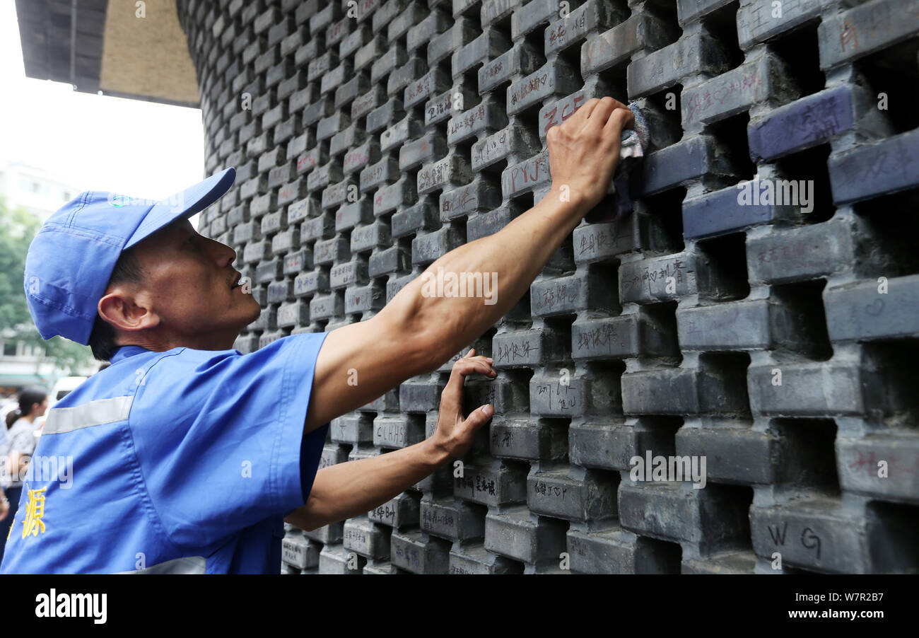 A Chinese cleaner scrubs graffiti off a wall left by unruly visitors at ...