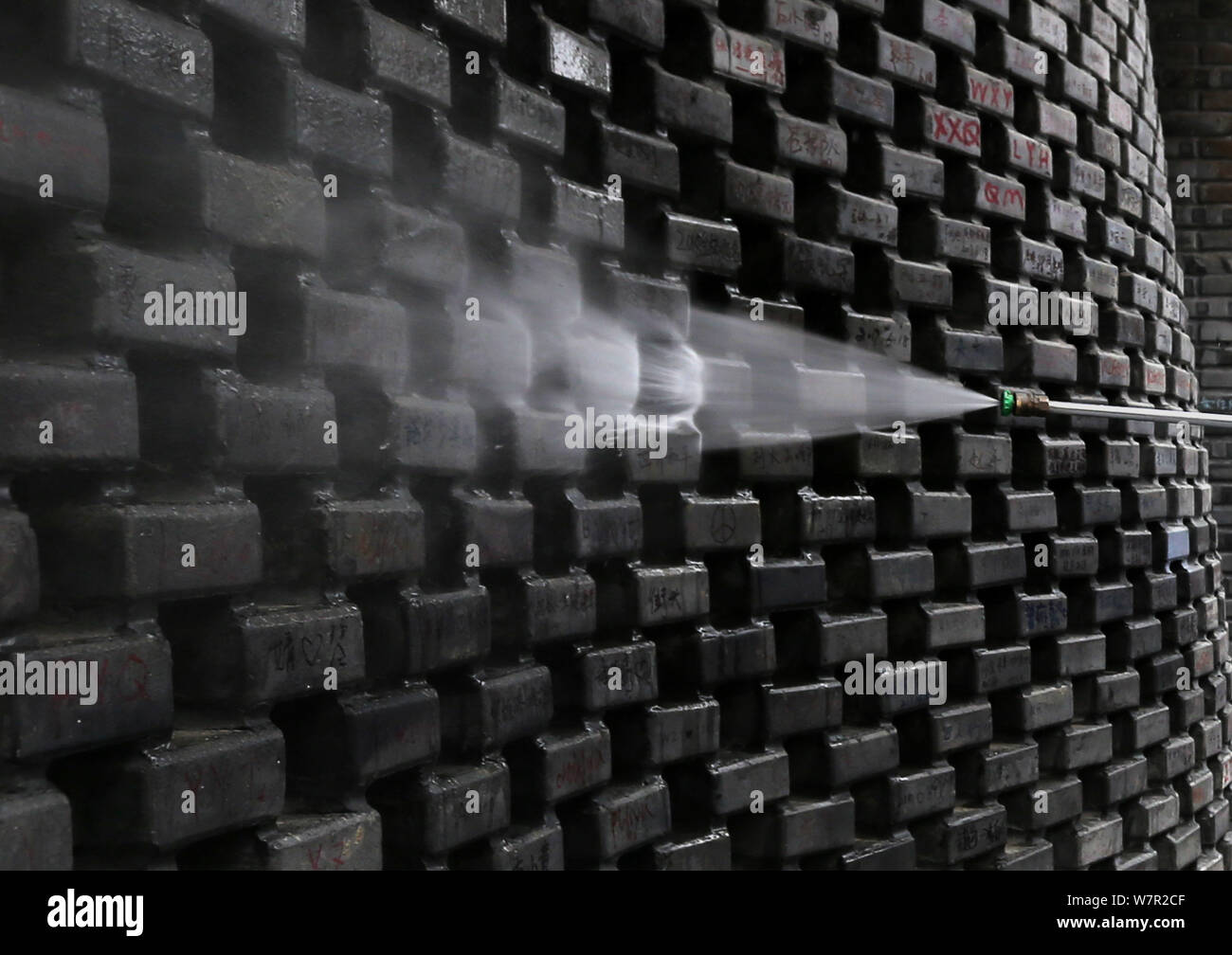 A Chinese cleaner sprays water to scrub graffiti off a wall left by ...