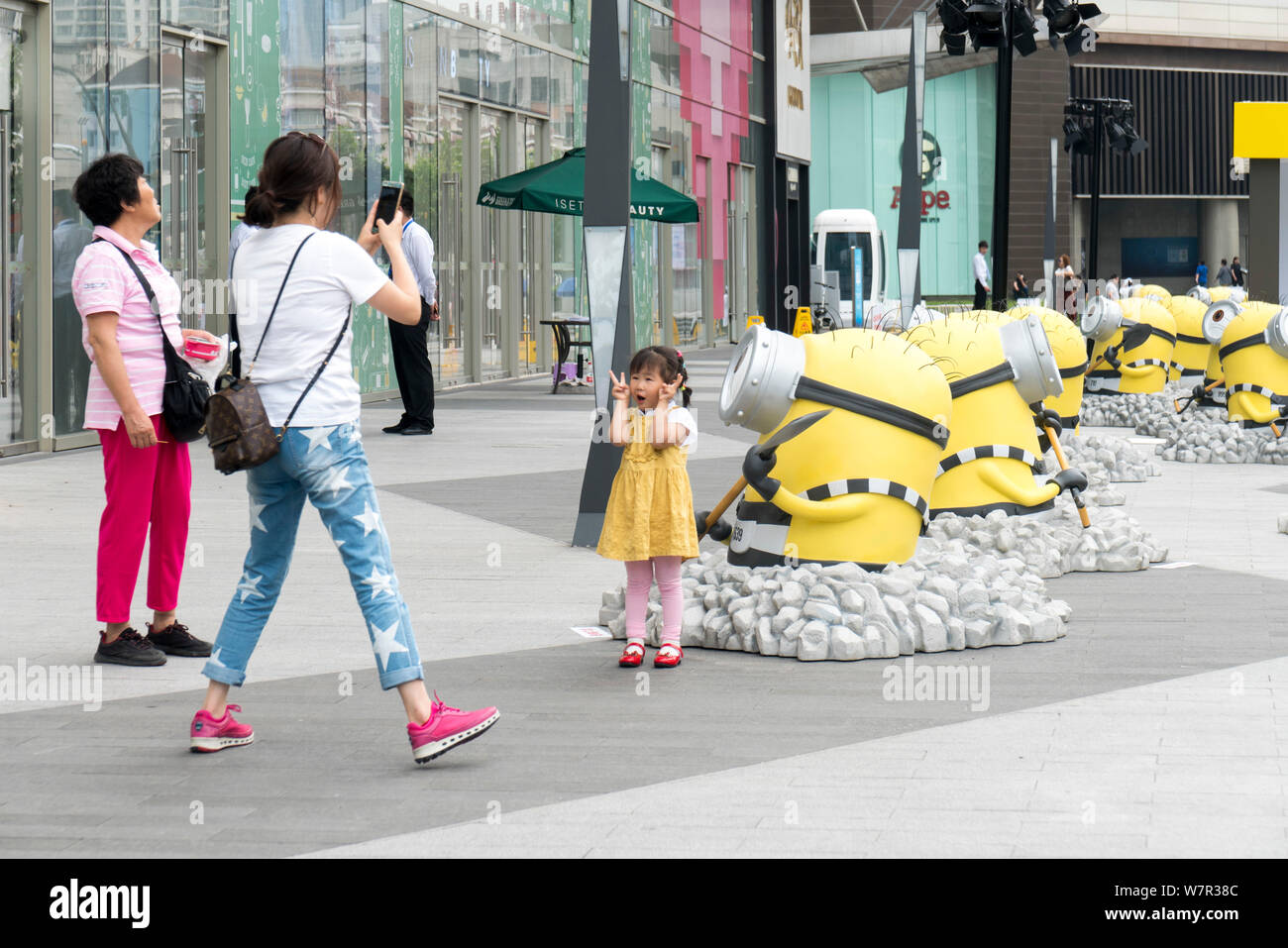 A Chinese girl takes photos with Minions-shaped sculptures armed with ...