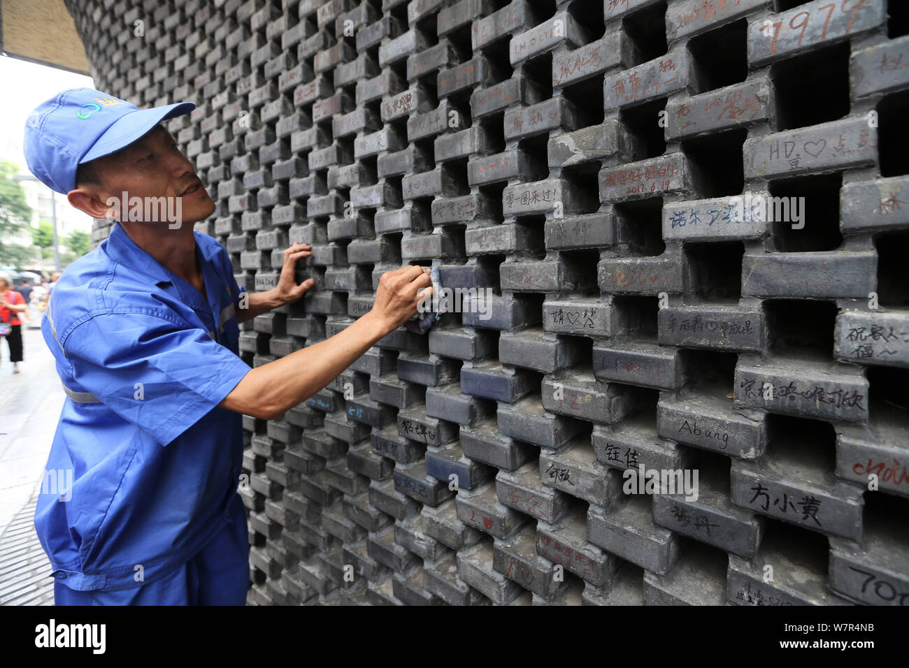 A Chinese cleaner scrubs graffiti off a wall left by unruly visitors at ...