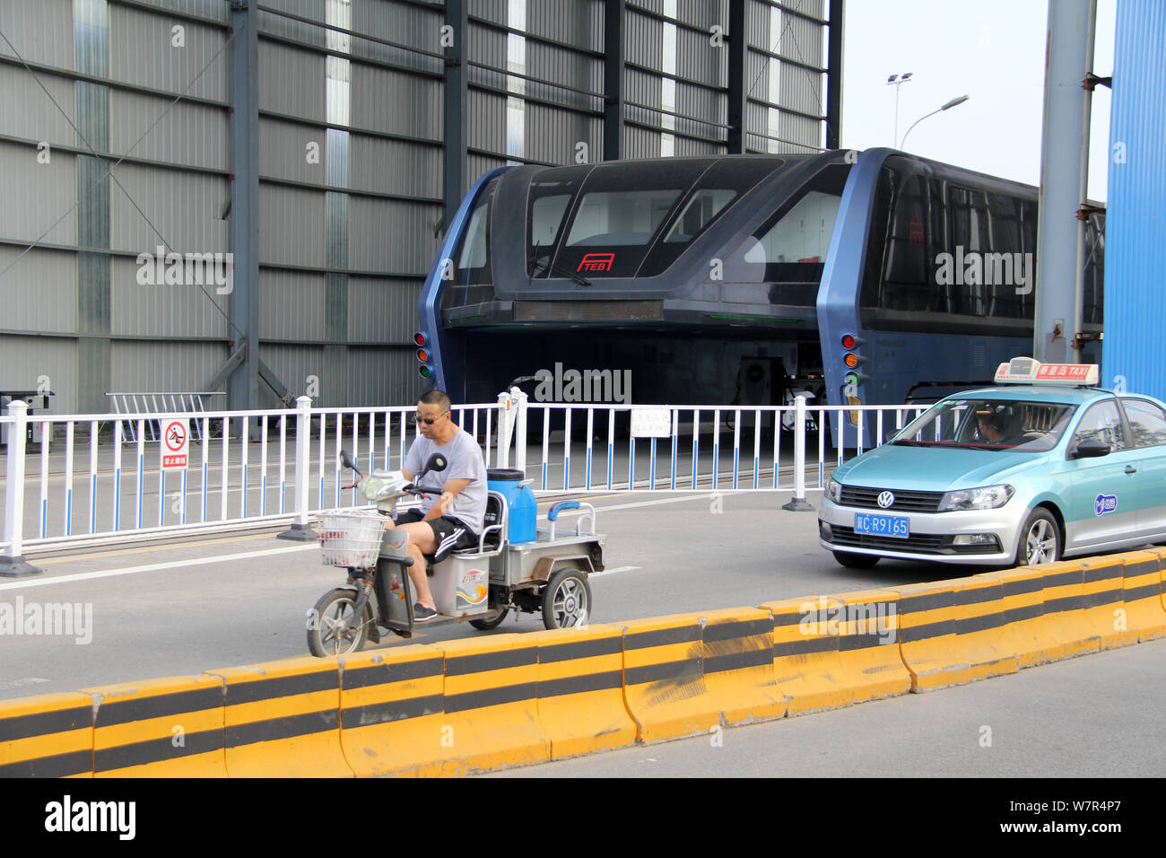 A car drives past the Transit Elevated Bus (TEB) on Fumin road in Qinhuangdao city, north China ...