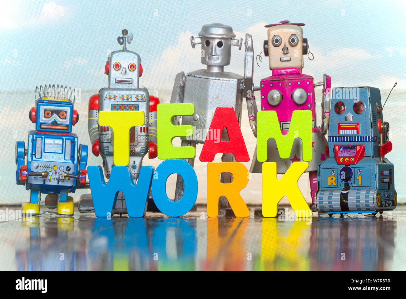 the word TEAM WORK with wooden letters and 5 retro bots on a wooden ...