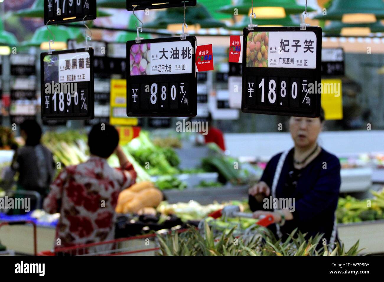Customers shop for vegetables at a supermarketi n Nanjing city, east ...