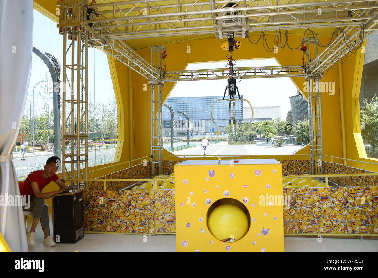 An employee is pictured in the huge grabbing machine featuring emojis ...