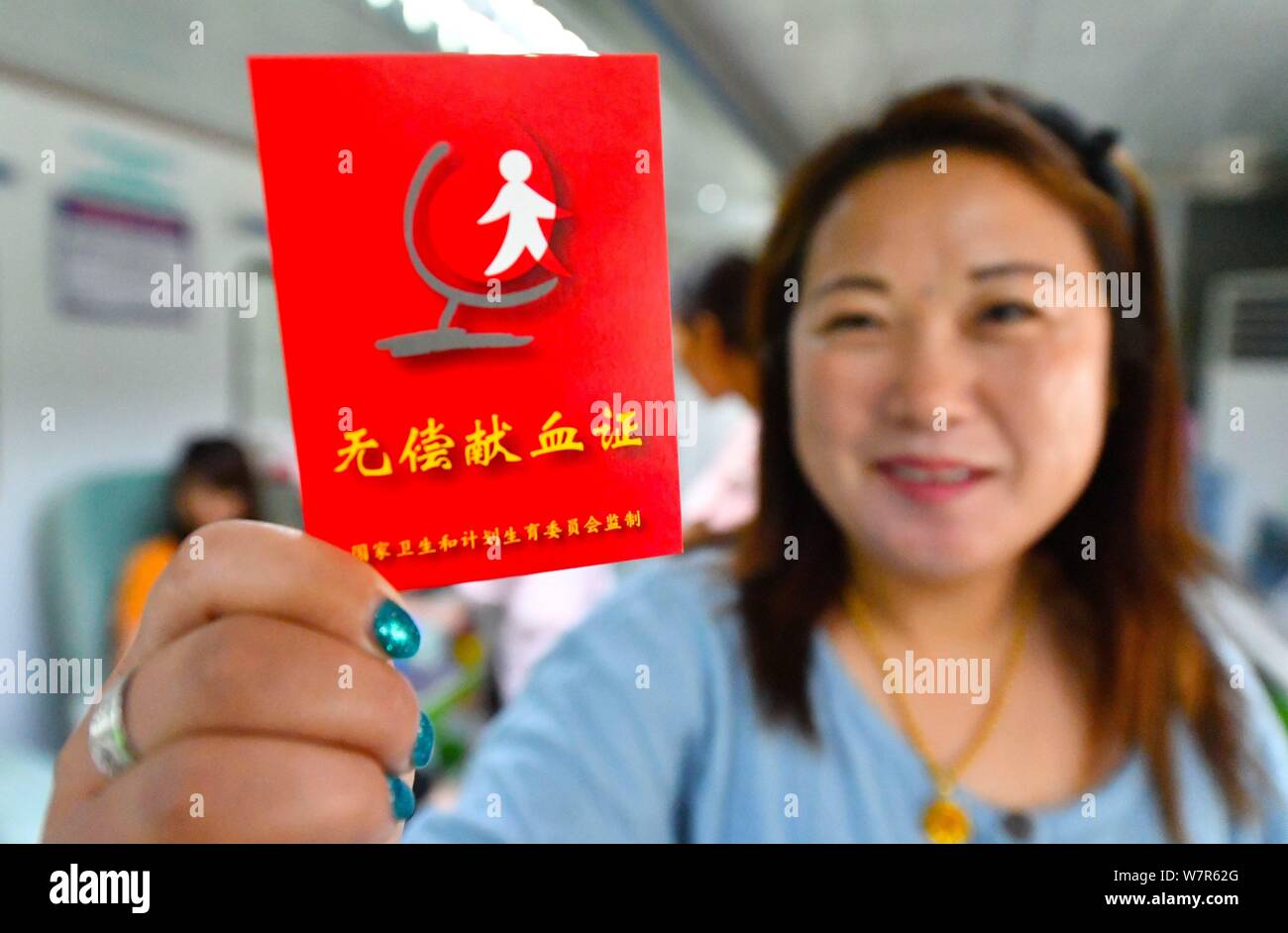 A Chinese citizen shows her blood donor card to mark the 14th World ...