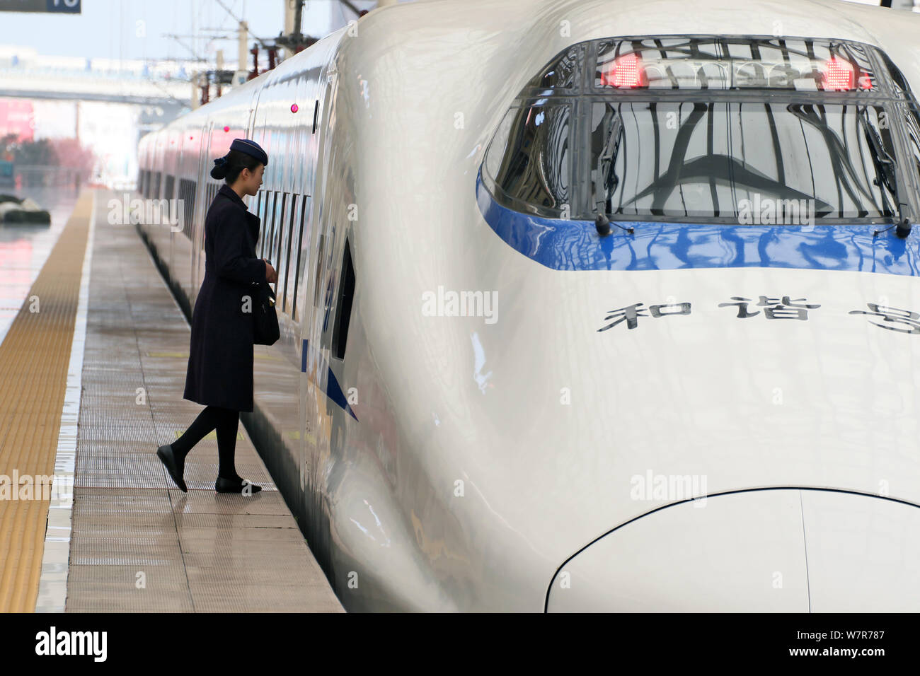 A Chinese attendant boards a CRH (China Railway High-speed) bullet ...
