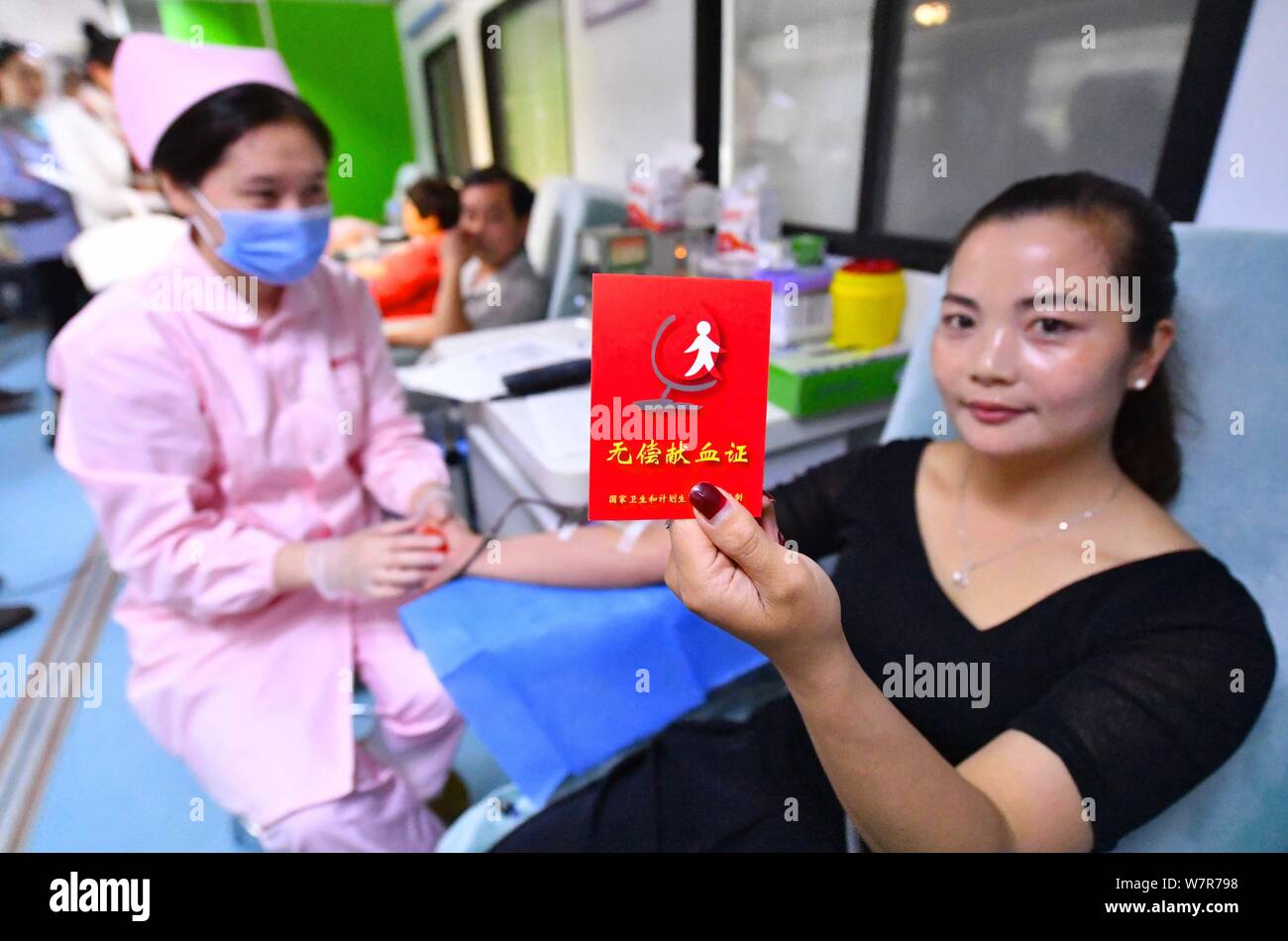 A Chinese citizen shows her blood donor card to mark the 14th World ...
