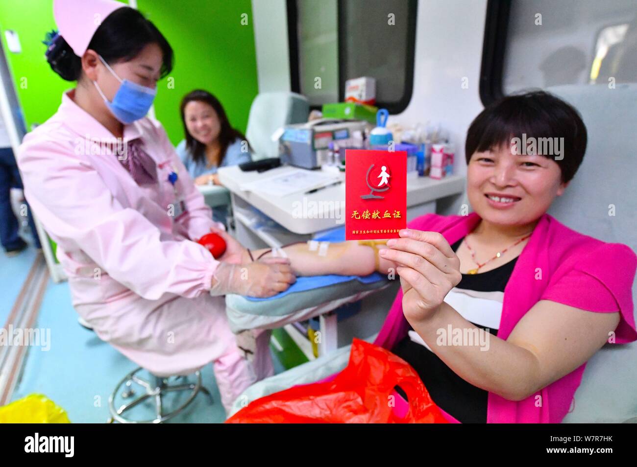 A Chinese citizen shows her blood donor card to mark the 14th World ...
