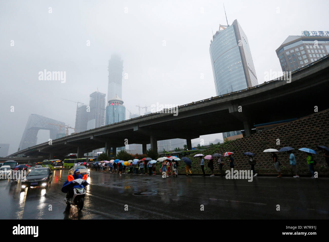 Chinese commuters shield themselves with umbrellas from heavy rain as ...
