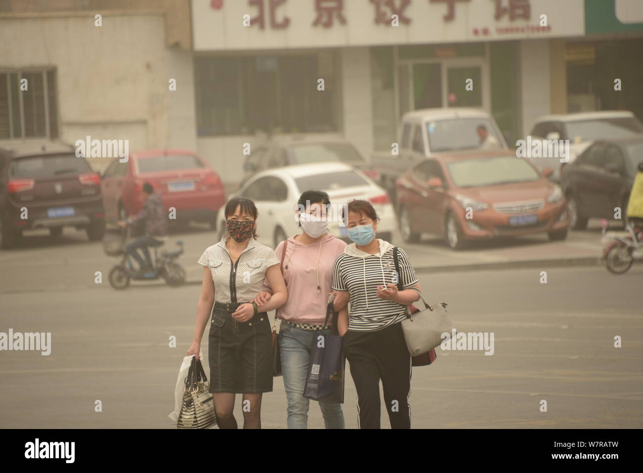 Local residents wearing face masks against air pollution walk on a road ...