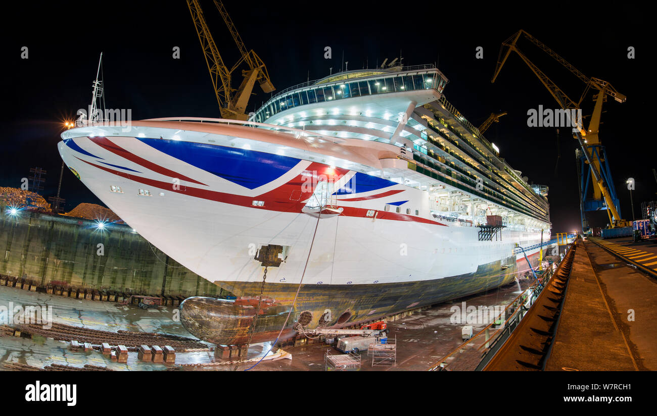 wide panoramic night time view of large cruise ship during dry dock ...