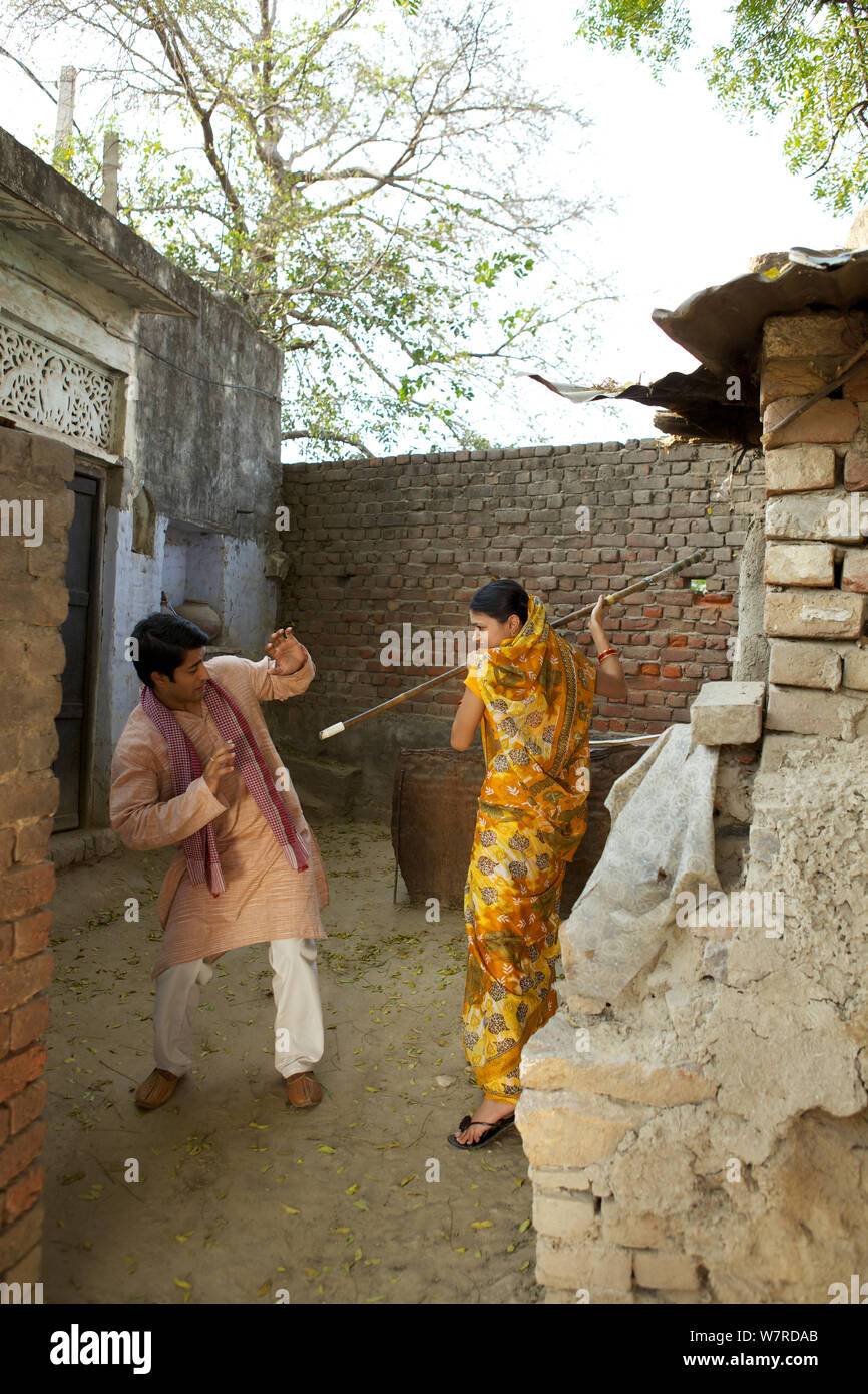 Rural woman hitting husband with cane Stock Photo - Alamy