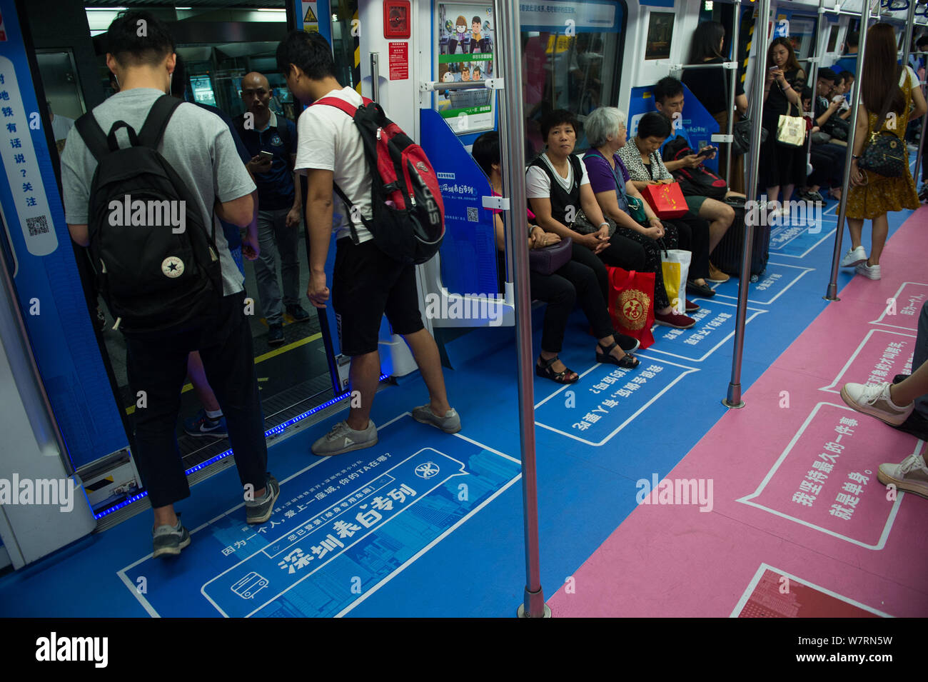 Chinese commuters are pictured in a subway train featuring pink and ...