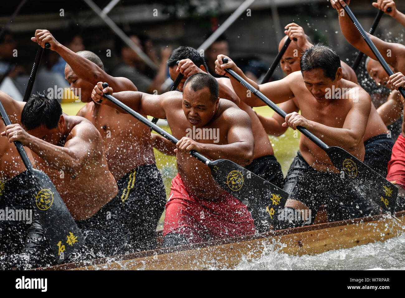 Participants compete in a dragon boat race on a river to celebrate the ...