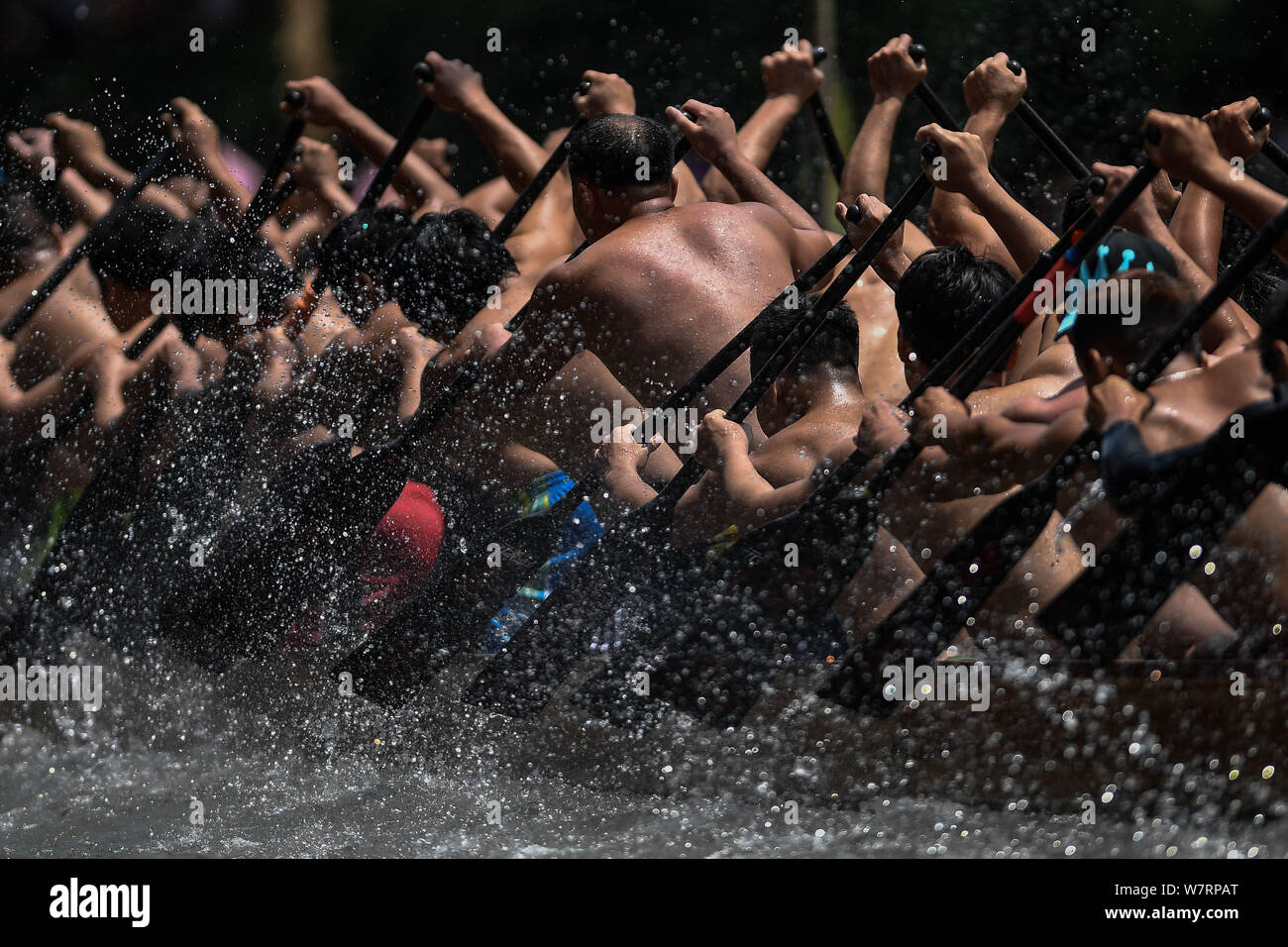 Participants compete in a dragon boat race on a river to celebrate the ...