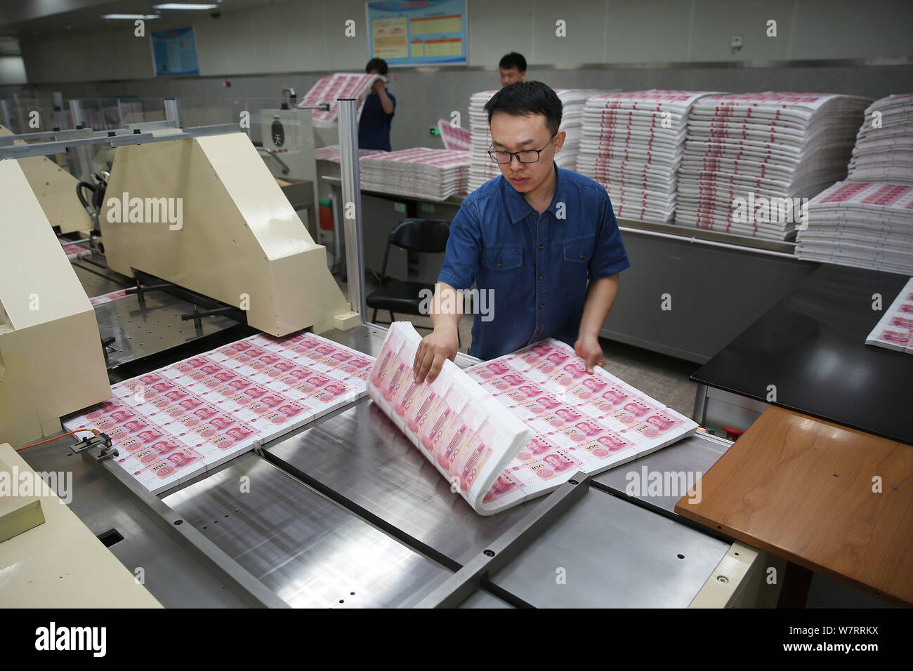 A Chinese worker cuts RMB (renminbi) yuan notes at a factory of ...