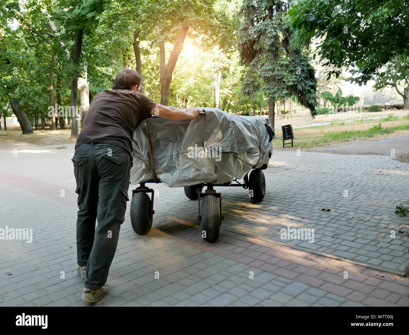 a homeless man pushes a cart in front of him Stock Photo - Alamy