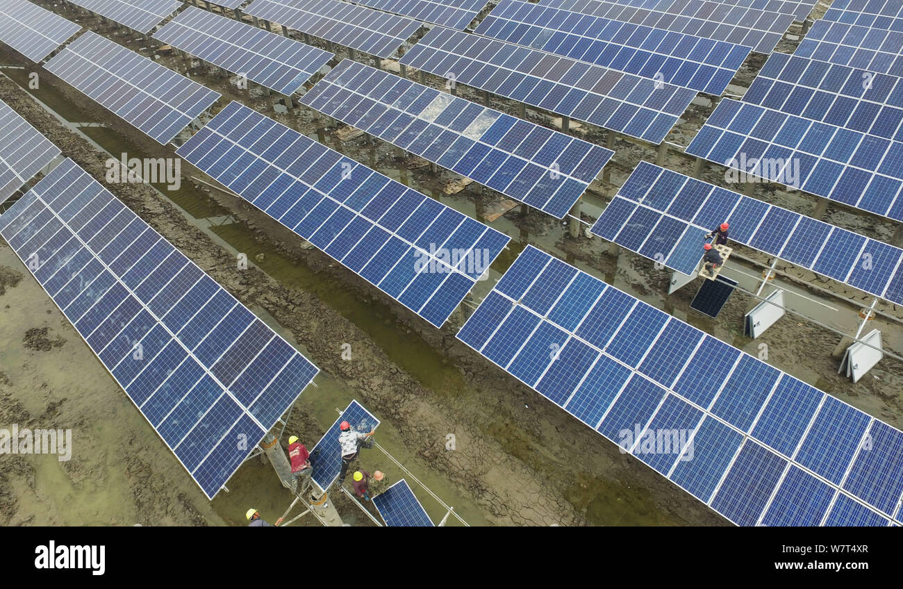 --FILE--Chinese workers install solar panels at a photovoltaic power ...