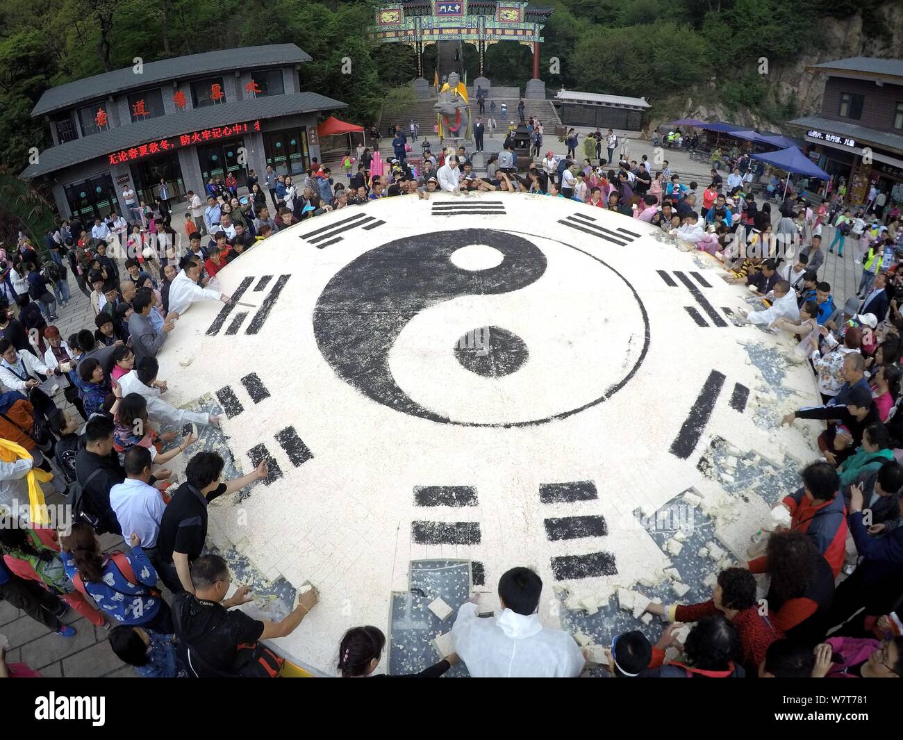 Tourists share giant tofu in the shape of a Tai Chi diagram during a ...
