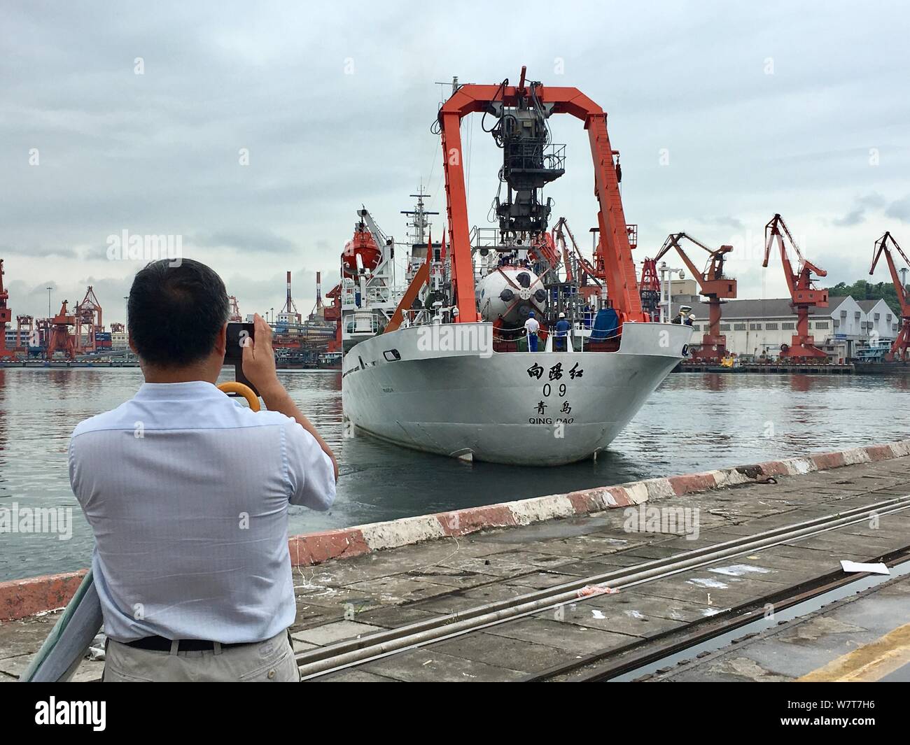 A Chinese employee takes photos of the Xiangyanghong 09 ship carrying ...