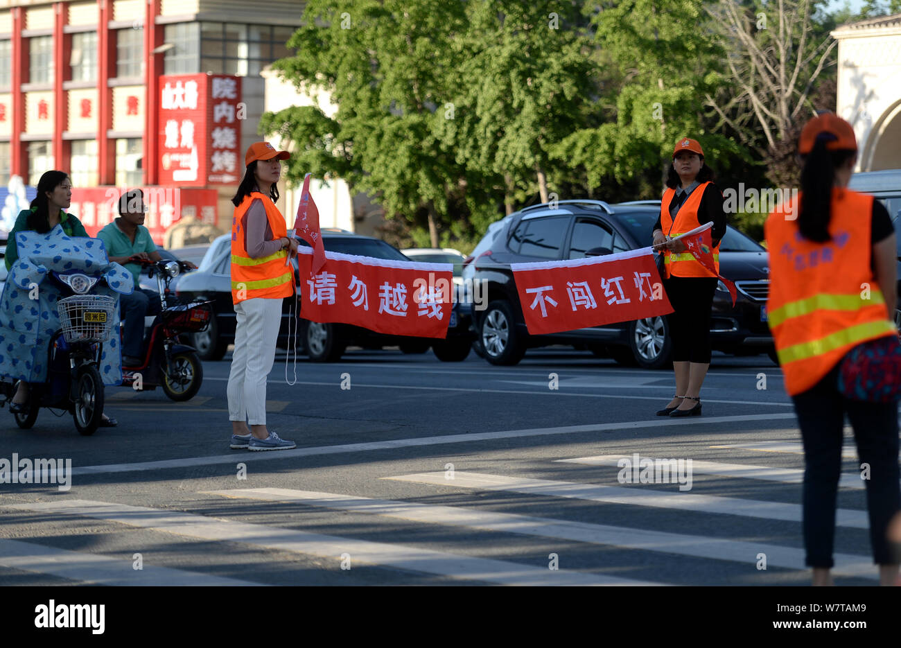 Chinese volunteers working as traffic order assistants use banners to ...