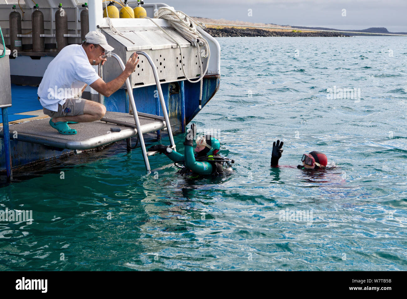 Dive master checking equipment and divers and giving the OK signal ...