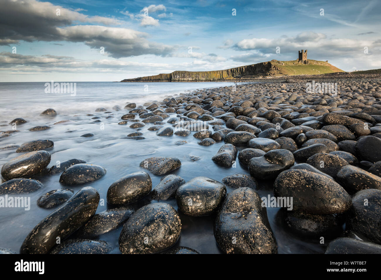 Round rocks on beach with Dunstanburgh Castlle in the distance ...