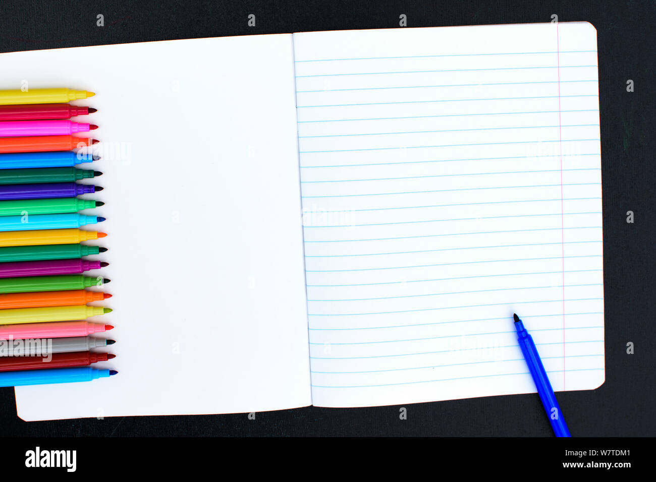 Open multicolored markers closeup on an open notebook in the line ...