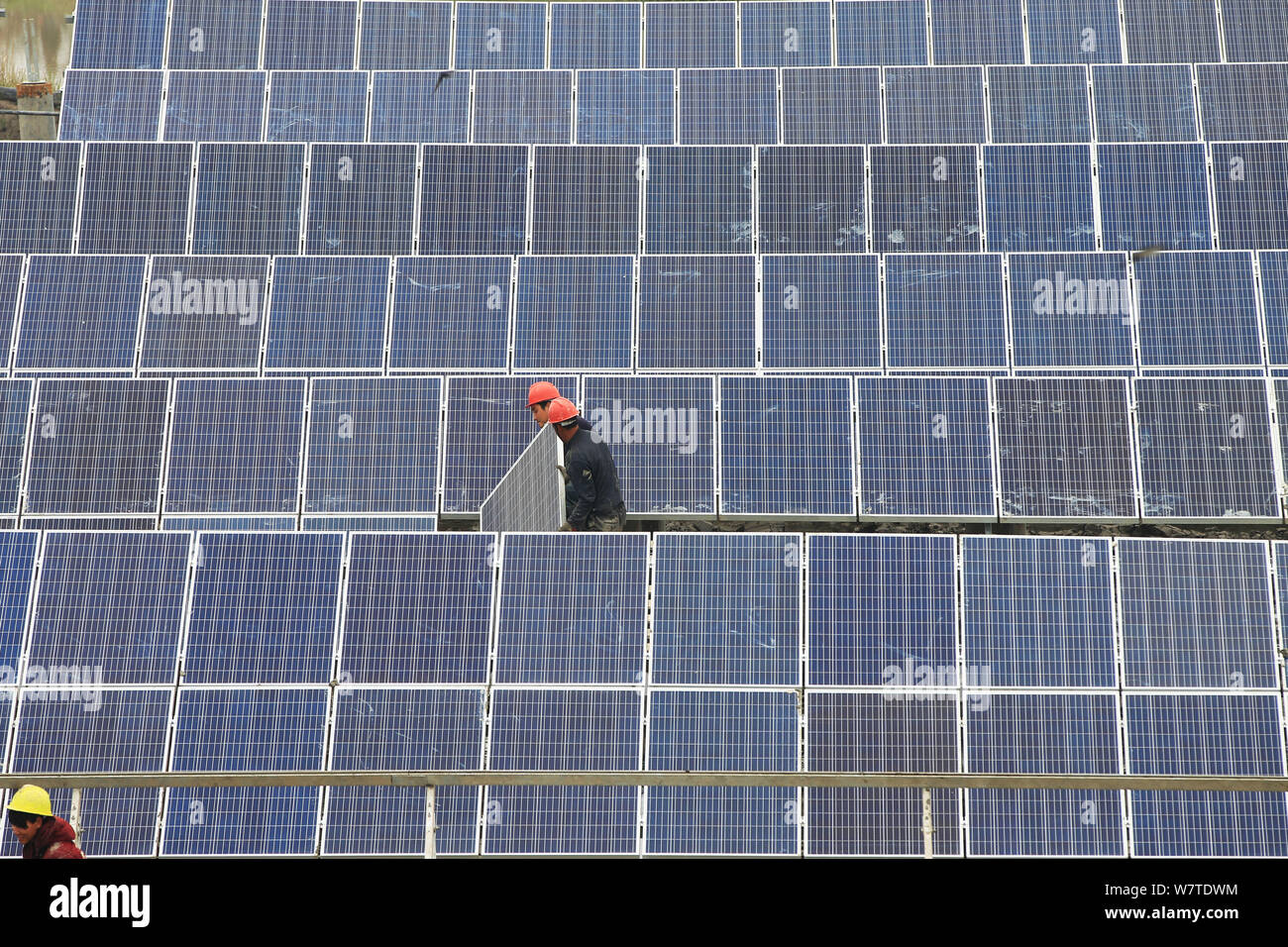 --FILE--Chinese workers install solar panels at a photovoltaic power ...