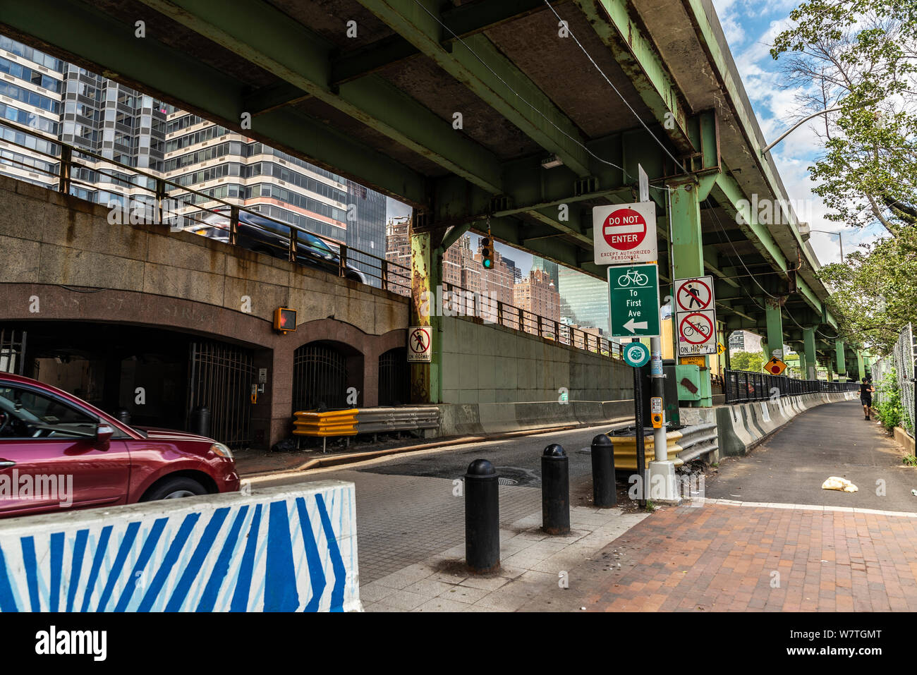 Road bridge and traffic signals with a man running next to East River ...