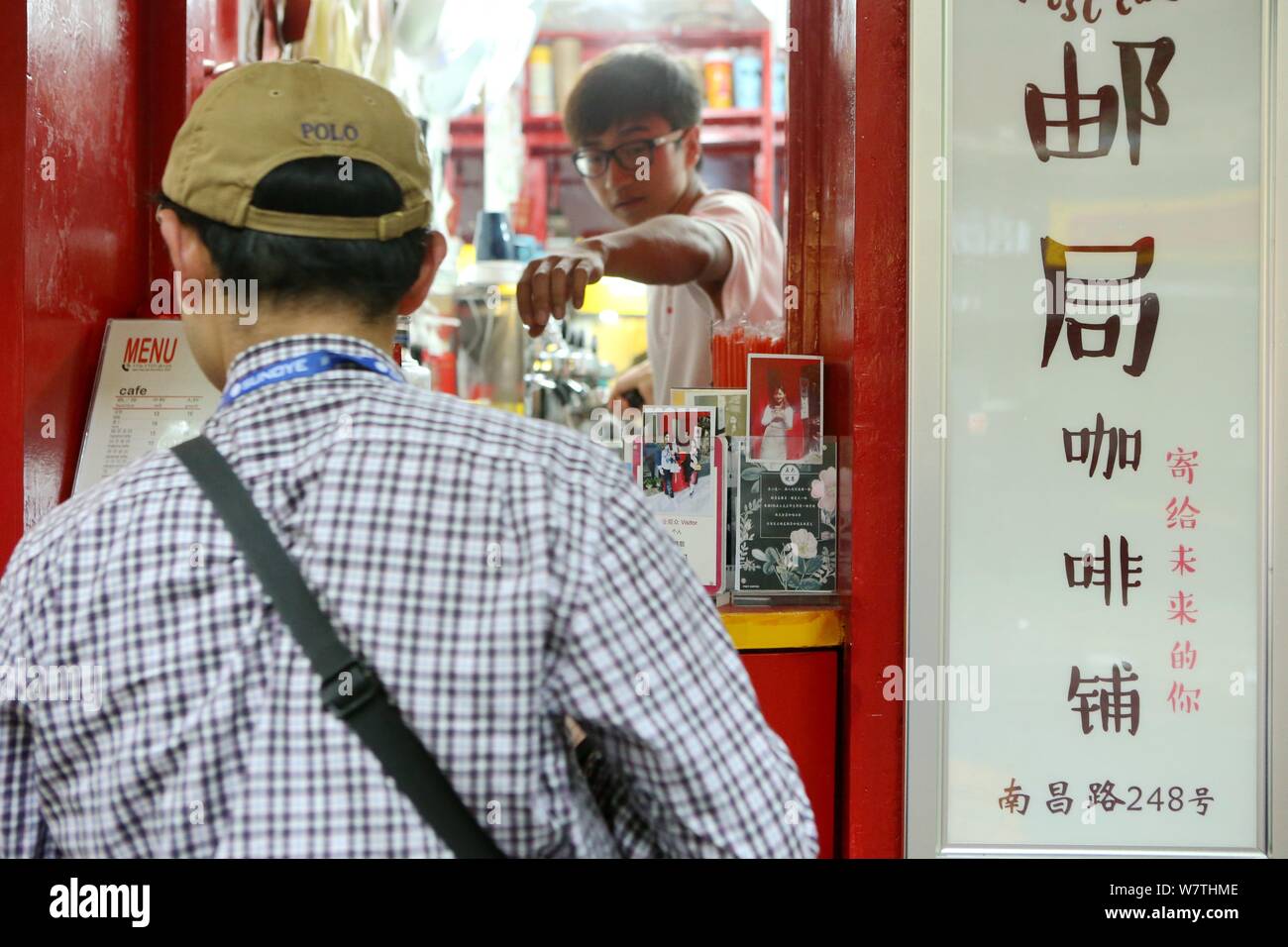 A customer looks at the menu in front of the tiny post cafe in Shanghai ...