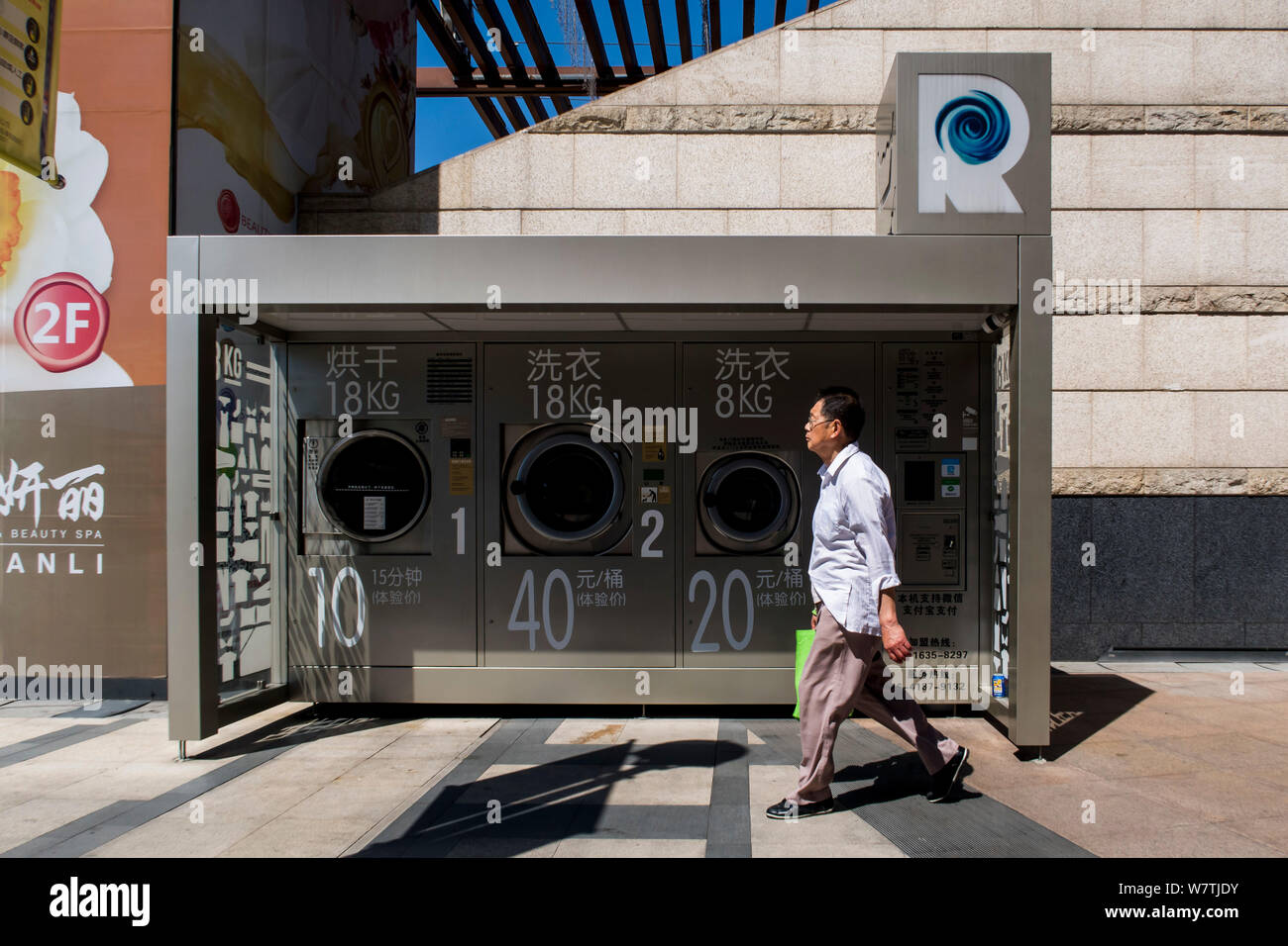A pedestrian walks past public washing machines installed outside a ...
