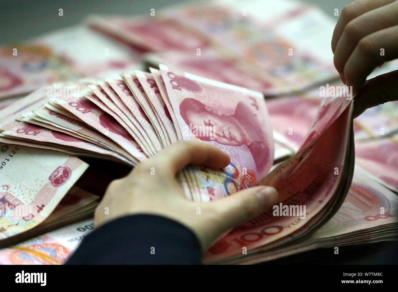 --FILE--A Chinese clerk counts RMB (renminbi) yuan banknotes at a bank ...