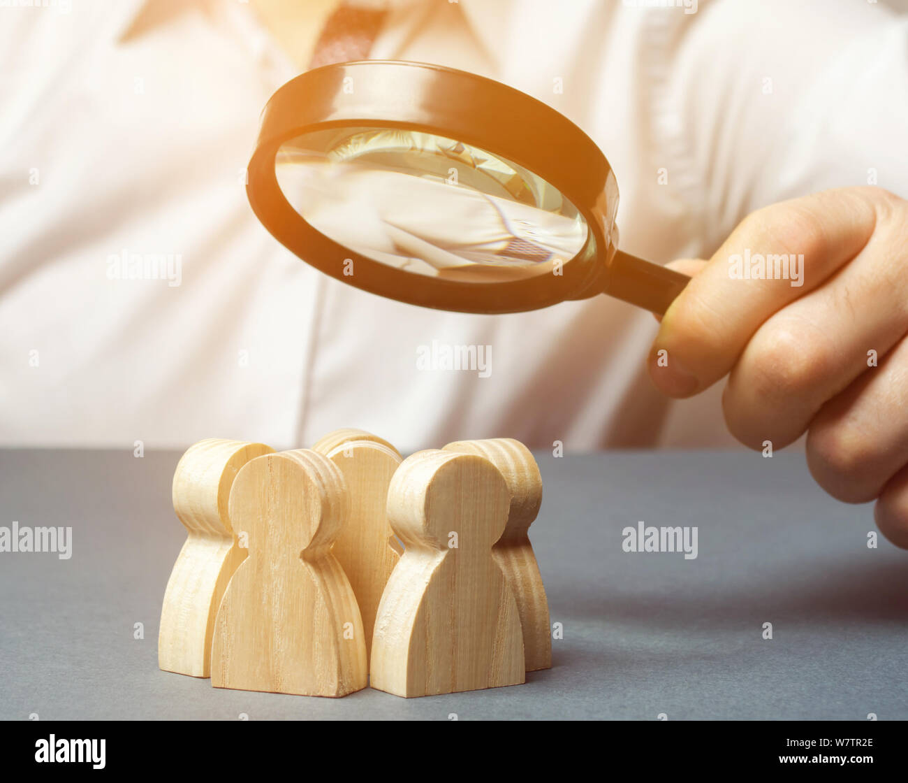Business leader holding a magnifying glass over a team of workers. The ...