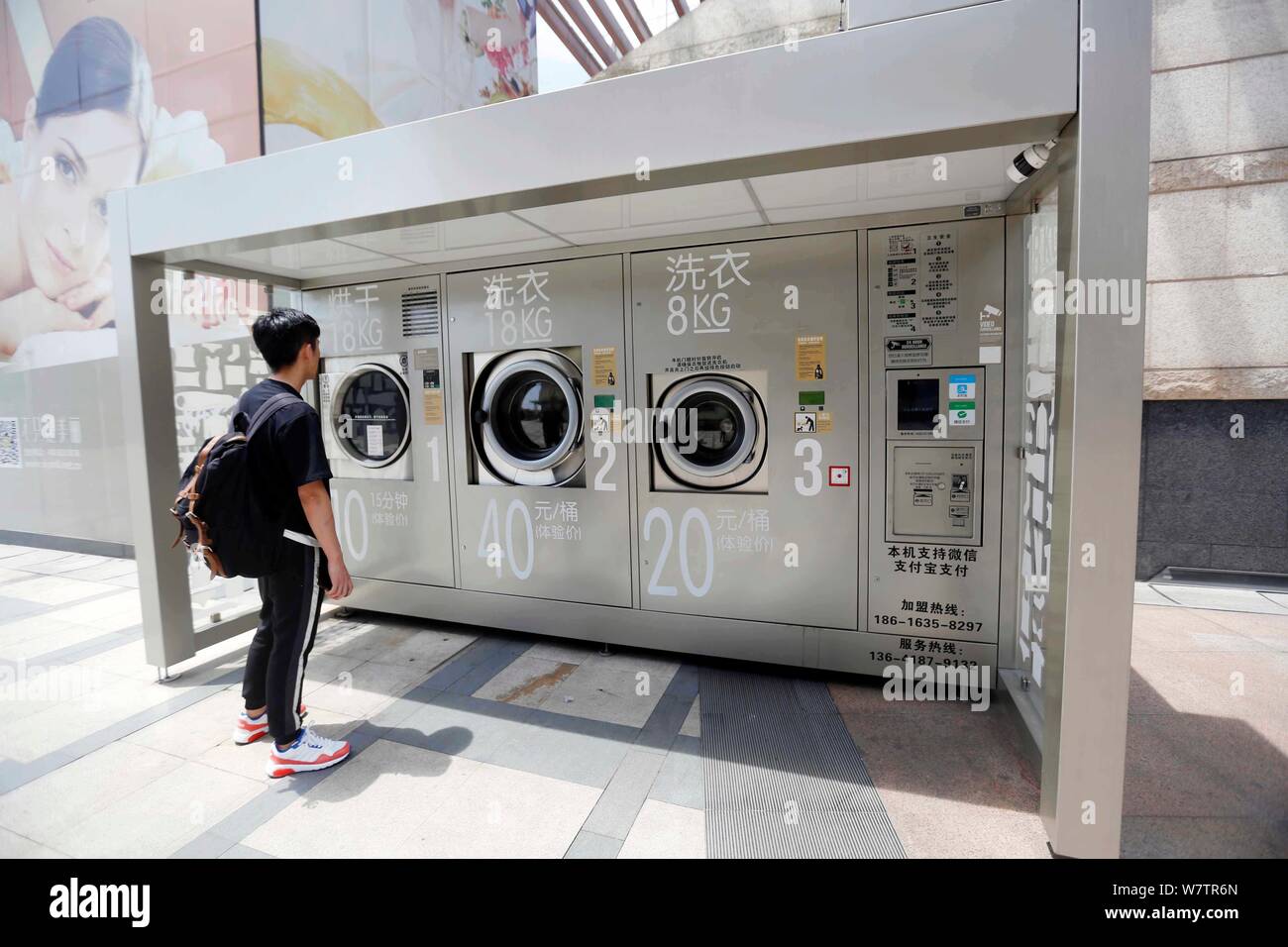 A customer looks at public washing machines installed outside a mall in ...