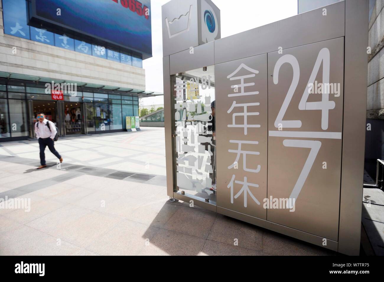 A pedestrian walks past public washing machines installed outside a ...