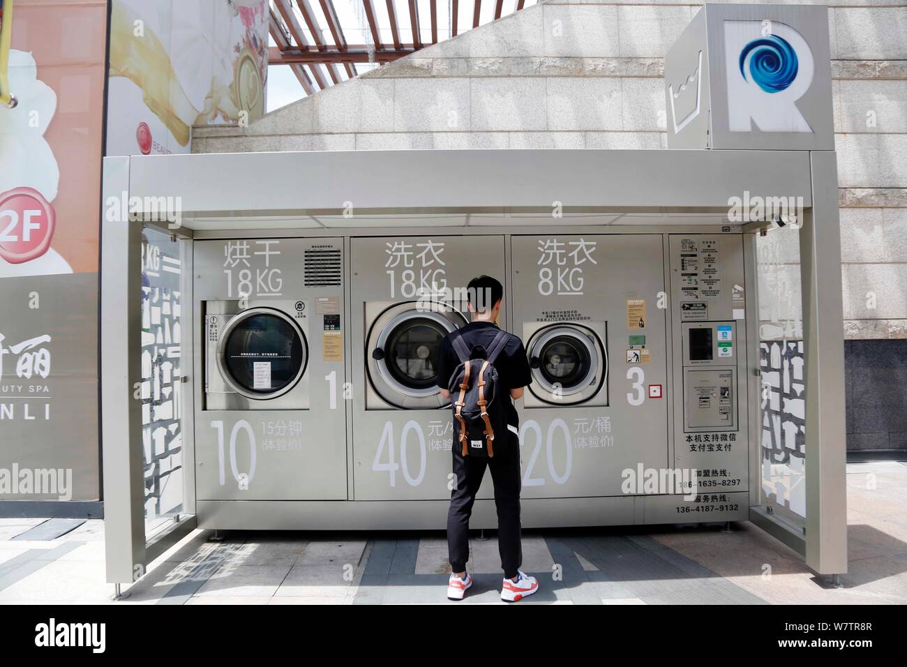 A customer looks at public washing machines installed outside a mall in ...