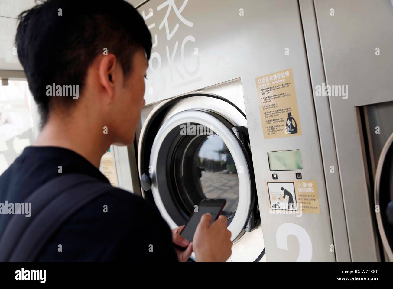 A mobile phone user tries to use a public washing machine installed ...