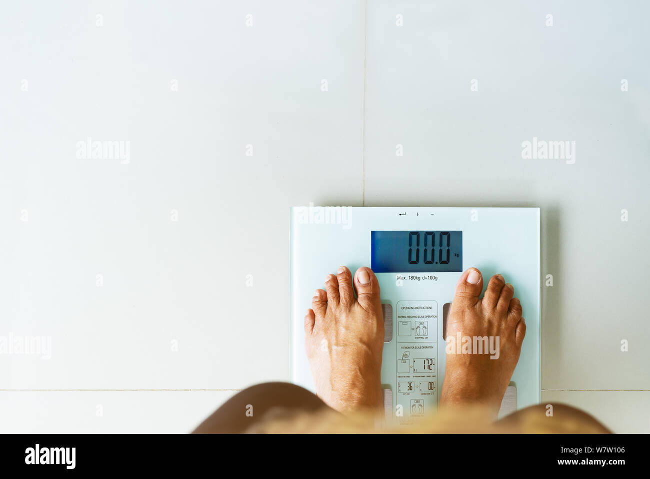 old woman standing on weight scale white color Stock Photo - Alamy