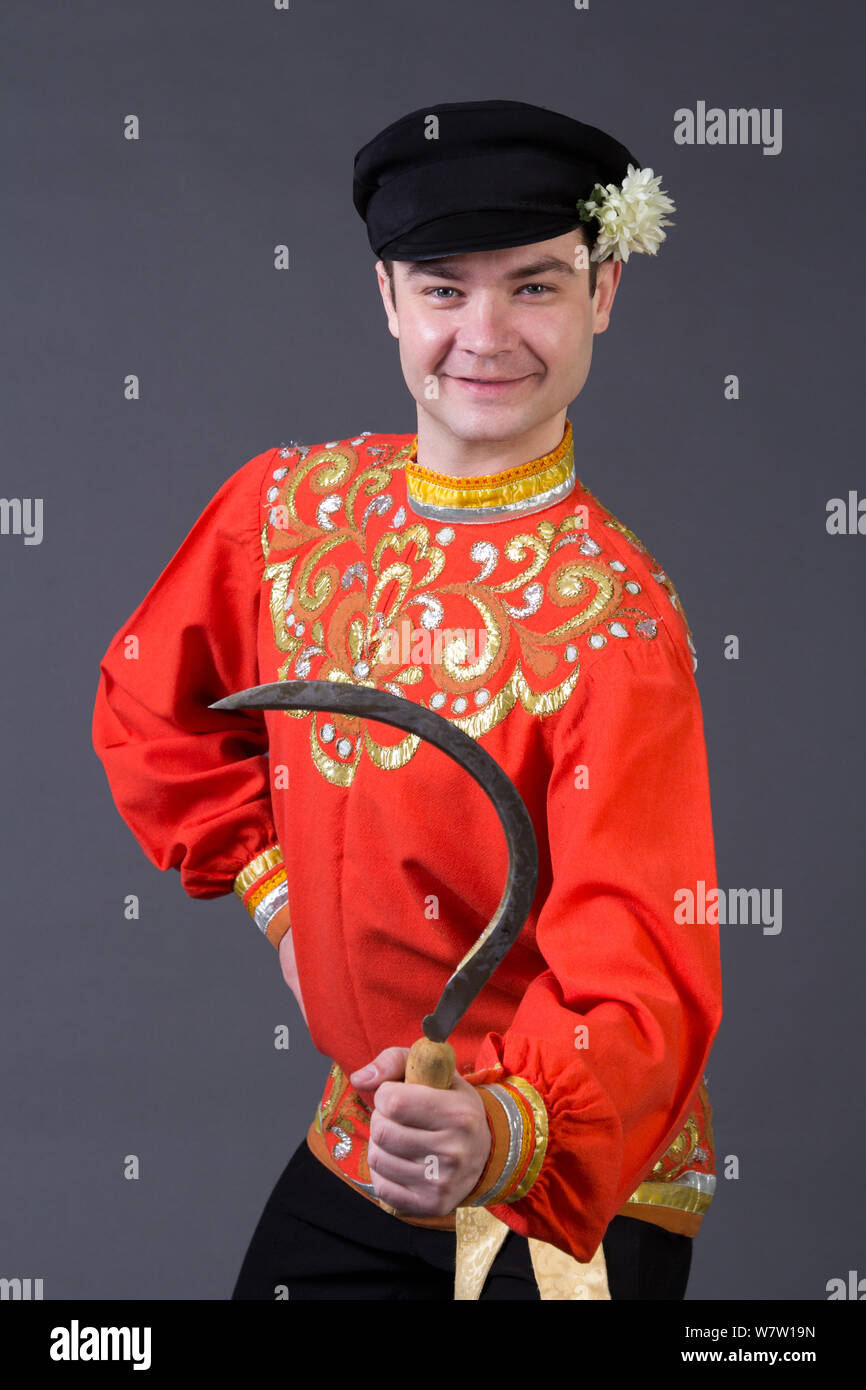 attractive russian guy with sickle in folk costume, studio picture ...